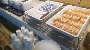 Uma disposição de buffet com várias estações de comida, incluindo lanches embalados e uma bandeja de camarão.