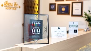 Uma receção com um prémio de avaliação de cliente emoldurado, um aviso com os horários de check-in/check-out e certificados emoldurados na parede.