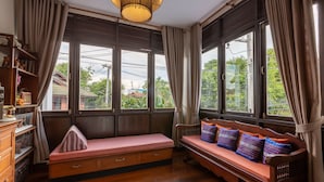 Quarto com um banco de madeira, uma cama pequena e uma estante.
