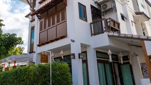 Um hotel de vários andares com fachada branca, varandas e área de entrada coberta.