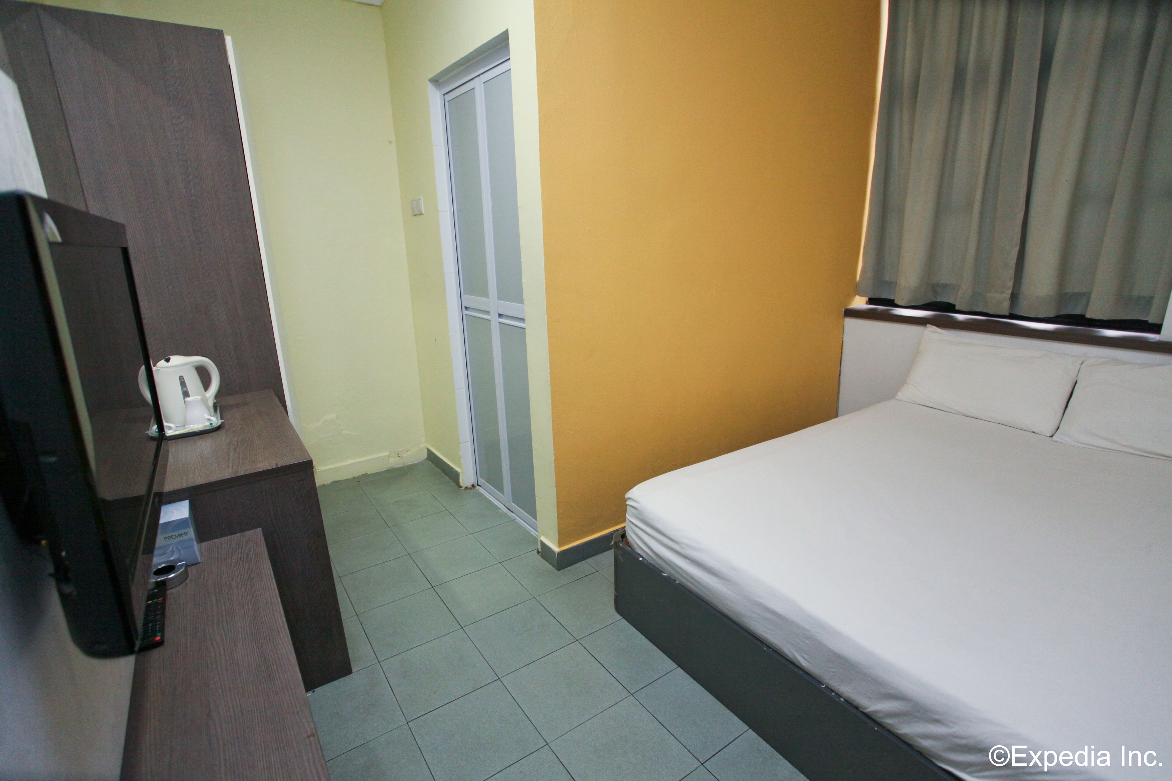 Quarto de hotel com uma cama, uma secretária com televisão e uma porta que dá para o banheiro.