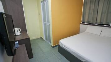 Quarto de hotel com uma cama, uma secretária com televisão e uma porta que dá para o banheiro.