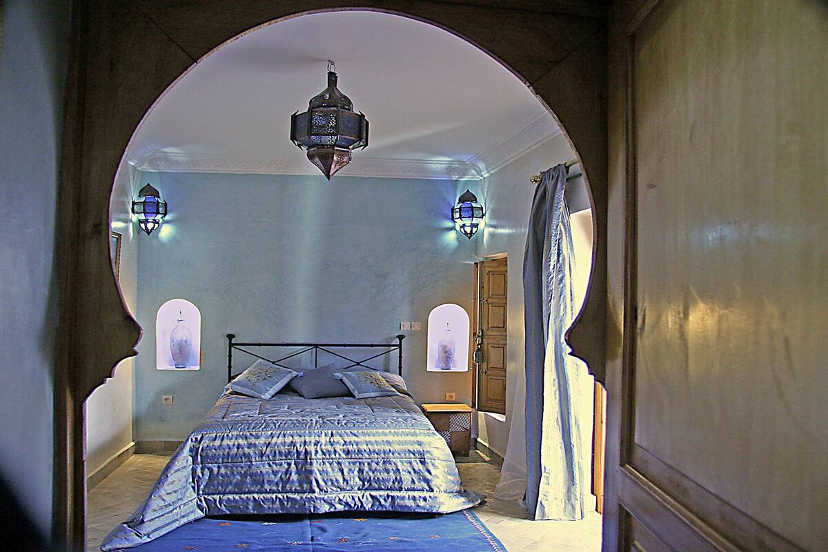 Quarto com cama, um candeeiro pendente e duas luminárias de parede.