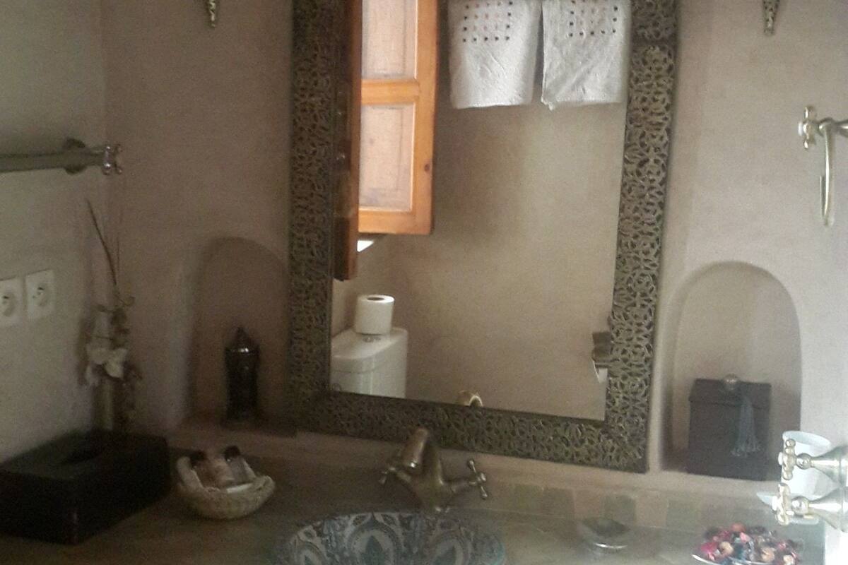 Casa de banho com lavatório, espelho e apliques decorativos.