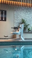 Uma área à beira da piscina com uma cadeira de rodas, uma parede texturizada e uma placa com ícones.