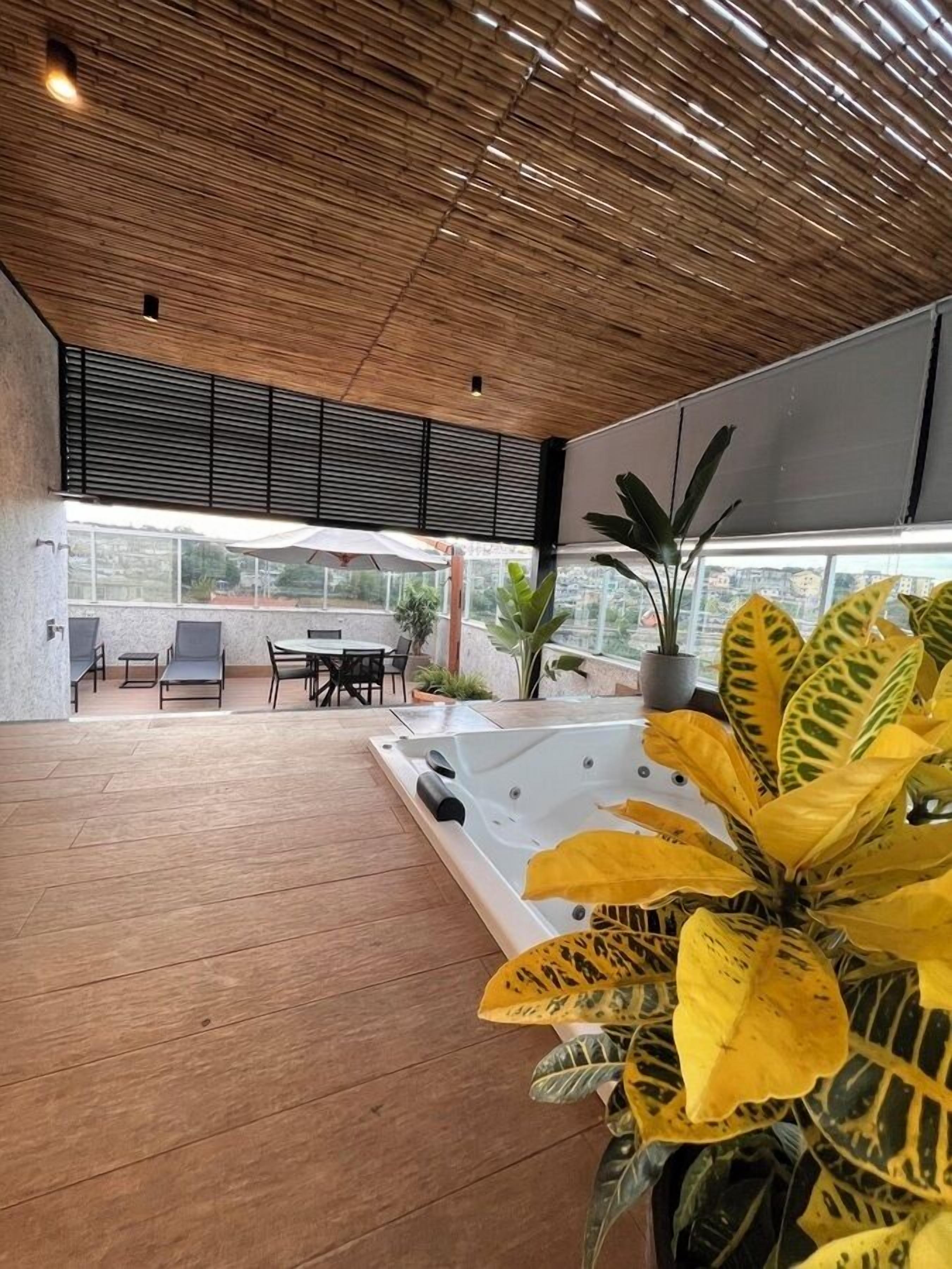 Um espaço moderno e interno com piso de madeira, uma banheira de hidromassagem e área de estar.