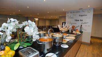 Uma área de buffet com diversos tipos de comida e um letreiro listando o cardápio em português.