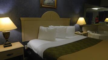 Quarto de hotel com cama, duas mesas de cabeceira com abajures, um criado-mudo, espelho e pia.