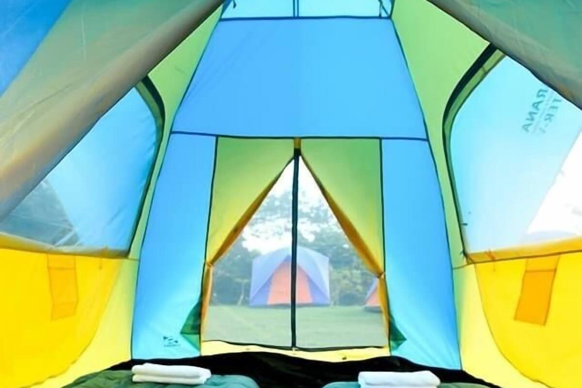 Uma tenda com duas camas, cada uma com almofadas e um cobertor.
