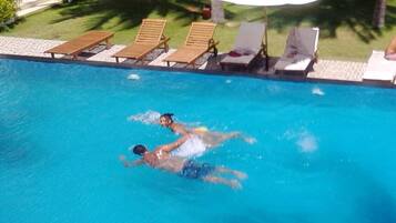 Uma piscina com espreguiçadeiras e guarda-sóis.