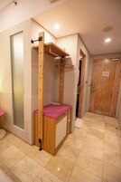 Quarto compacto com estrutura de cama de madeira, uma pequena mesa e uma porta.