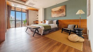 Quarto moderno com cama, uma cadeira, um abajur e vista para o exterior.