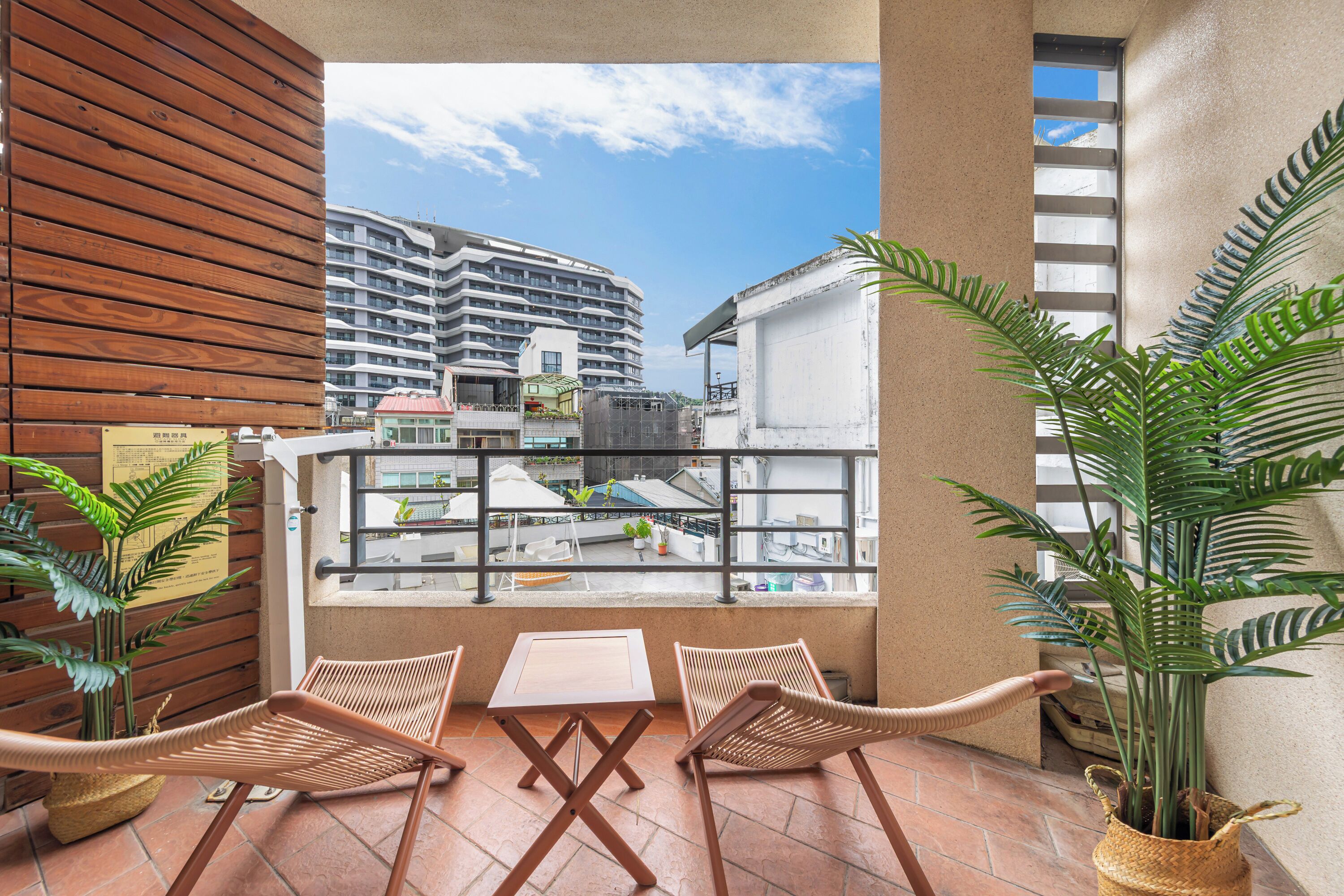 Varanda com cadeiras de vime e uma mesa, com vista para um horizonte urbano repleto de edifícios modernos.