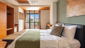 Quarto de hotel moderno com uma cama grande, uma escrivaninha e vista da cidade através de amplas janelas.