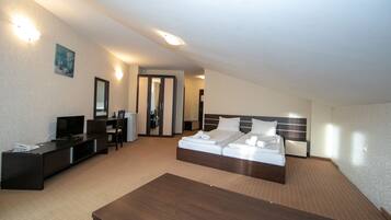 Quarto de hotel com cama, televisão, escrivaninha e espelho.