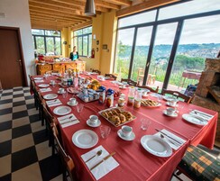 Uma área de refeições com toalha de mesa vermelha, pratos brancos e diversas opções de café da manhã.