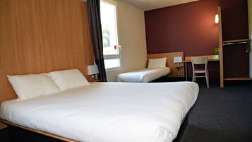 Quarto de hotel com uma cama grande, uma cama menor, uma escrivaninha e uma cadeira.