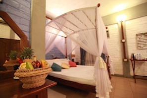 Quarto com cama sob dossel, cesta de vime com frutas e um painel de avisos na parede.