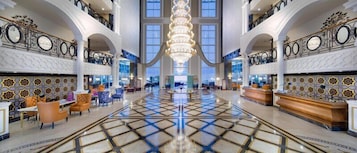 Um hall amplo com um lustre imponente, várias áreas de estar e um balcão de check-in.