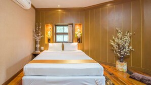 Quarto de hotel com uma cama grande, painéis de parede de madeira, uma janela com cortinas e vasos decorativos.