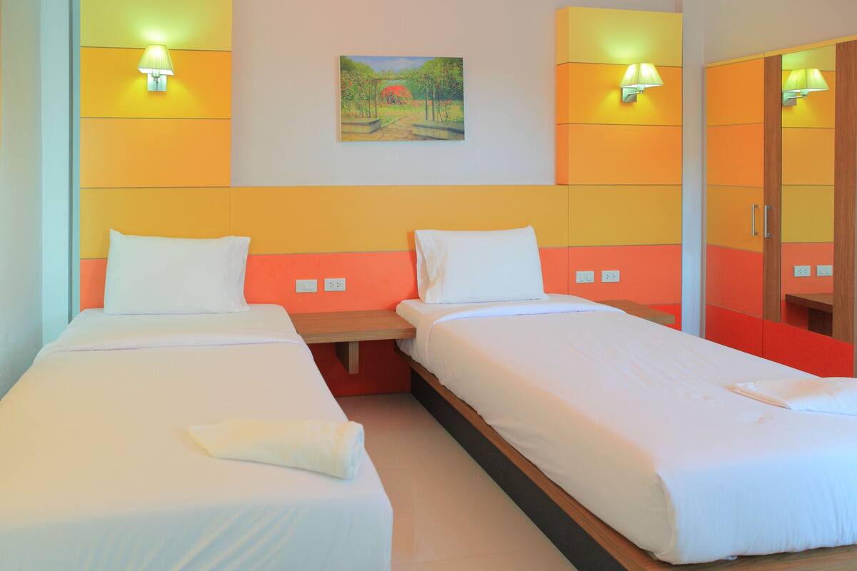 Quarto de hotel com duas camas de solteiro, um quadro na parede e um armário com espelho.