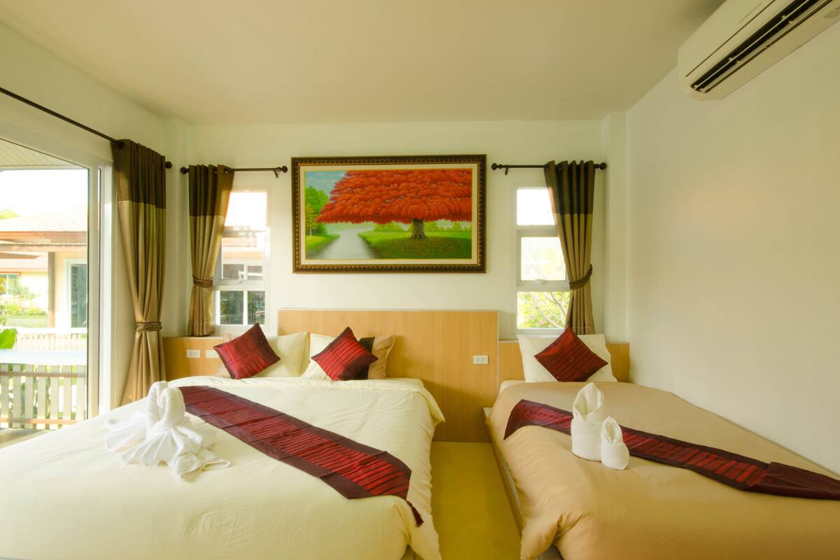 Quarto de hotel com duas camas, um quadro de uma árvore e vista para o exterior.