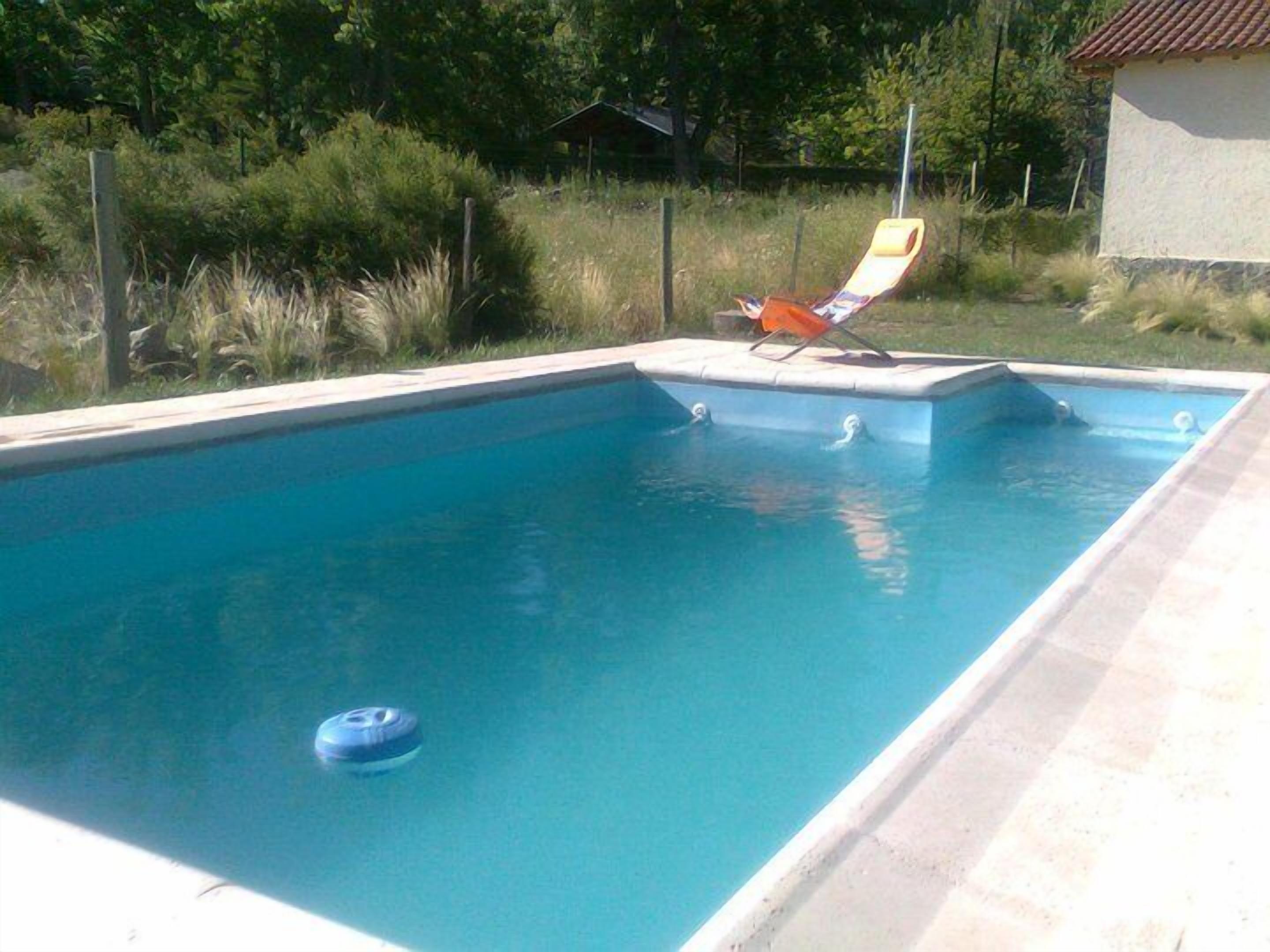 Uma piscina retangular com uma espreguiçadeira e um objeto flutuante.