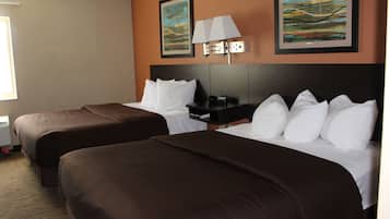 Quarto de hotel com duas camas, uma mesa de cabeceira e duas pinturas na parede.