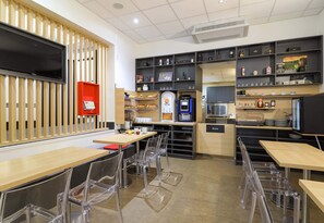 Um restaurante moderno com cadeiras de plástico transparente, mesas de madeira e uma variedade de alimentos e bebidas nas prateleiras.