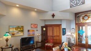 Uma sala de estar espaçosa com televisão, móveis de madeira e obras de arte nas paredes.