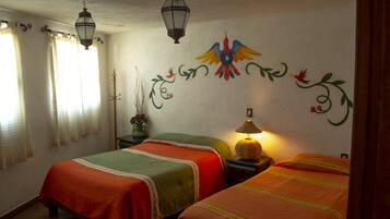 Quarto com duas camas, um mural na parede e duas lanternas penduradas.