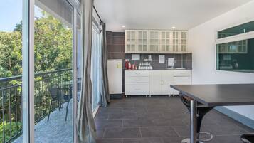 Uma cozinha moderna com armários brancos, bancada preta e varanda com vista para áreas verdes.