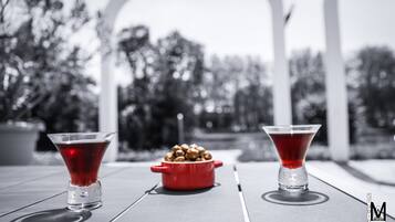 Dois copos de martini com líquido vermelho sobre uma mesa, um pote vermelho com nozes e o logotipo 'Studio M' em um apoio para copos.
