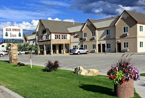 Blue Spruce Inn com fachada de pedra, várias varandas e um estacionamento.