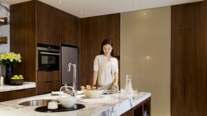 Cozinha moderna com armários de madeira, bancada de mármore e eletrodomésticos de aço inoxidável.