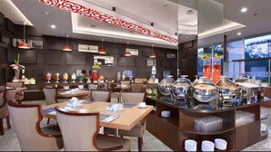 Espaço de refeições estilo buffet, com diversas estações de serviço e arranjos de assentos.