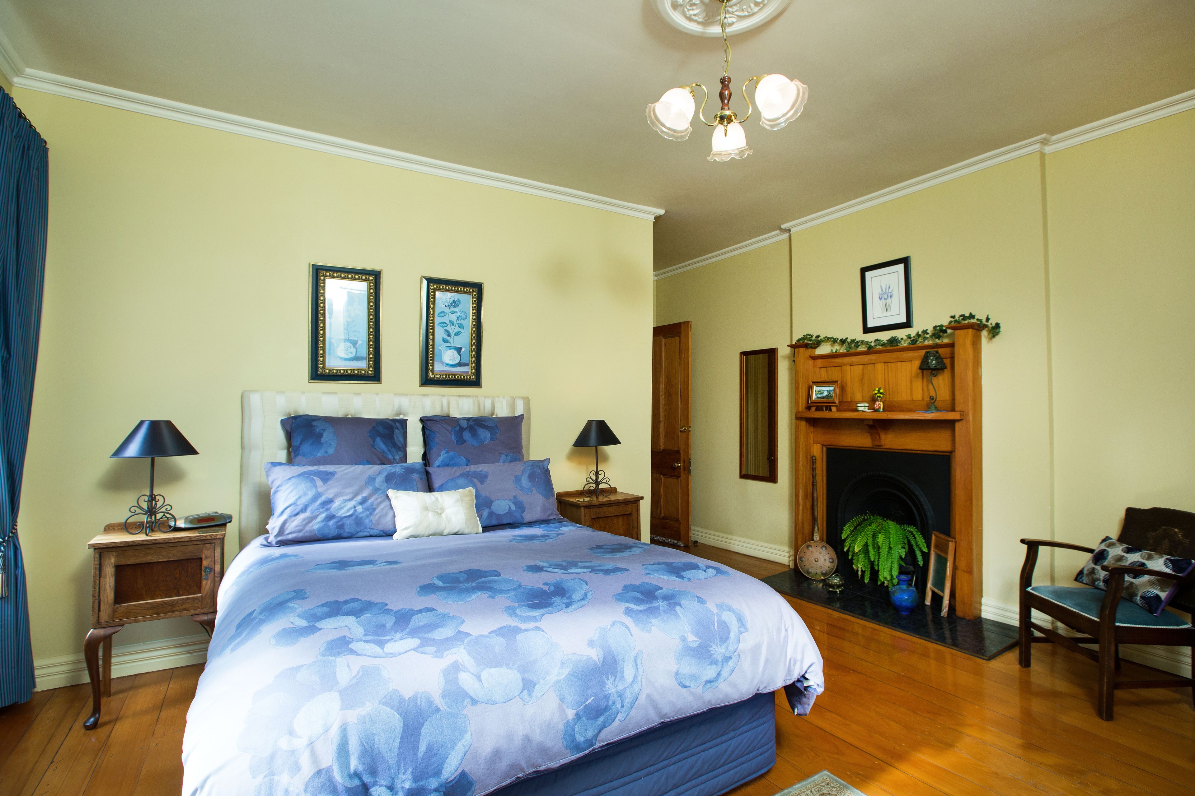 Quarto com cama grande, duas mesas de cabeceira, lareira e uma cadeira.