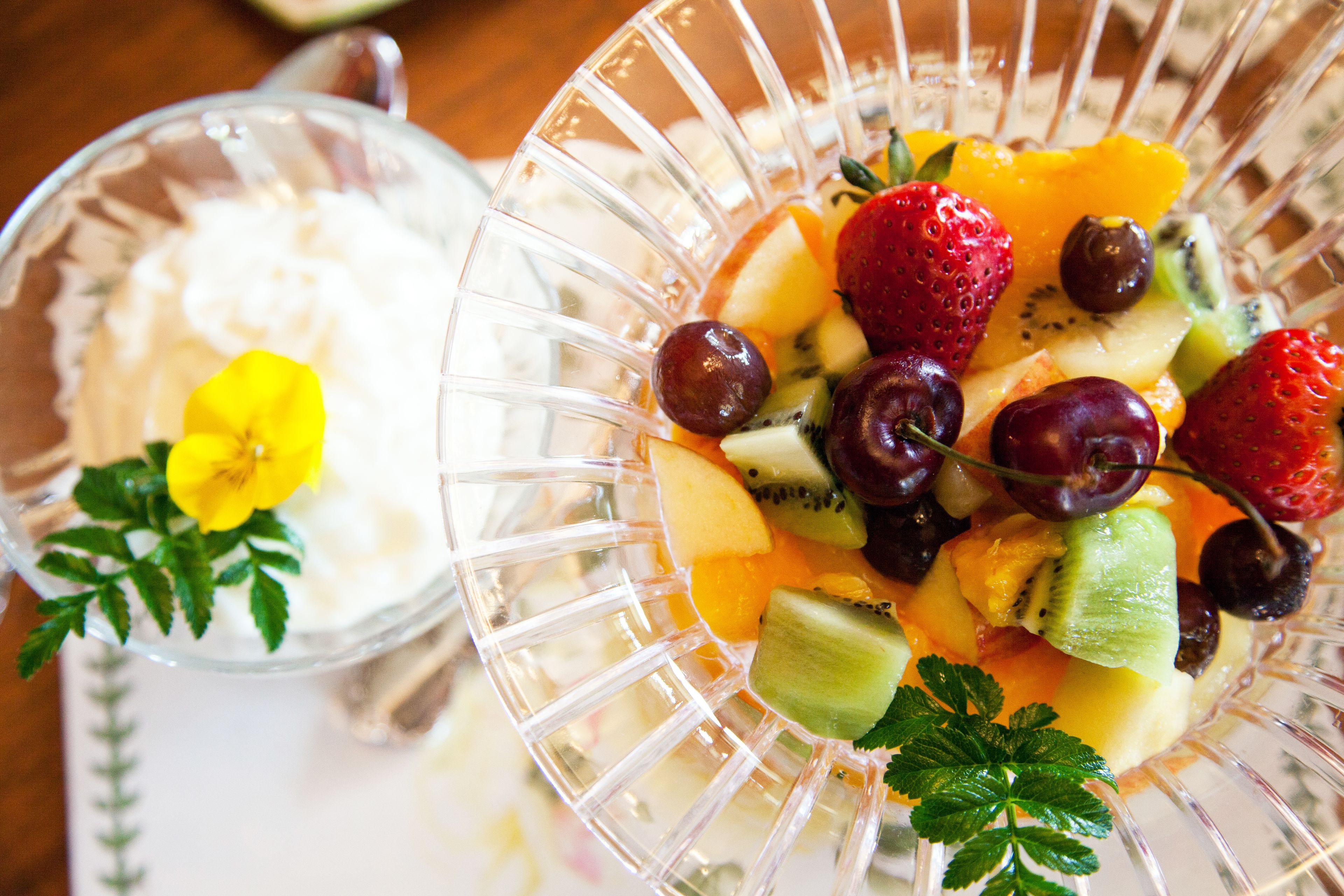 Uma salada de frutas com morangos, uvas, kiwi e outras frutas em uma tigela de vidro.