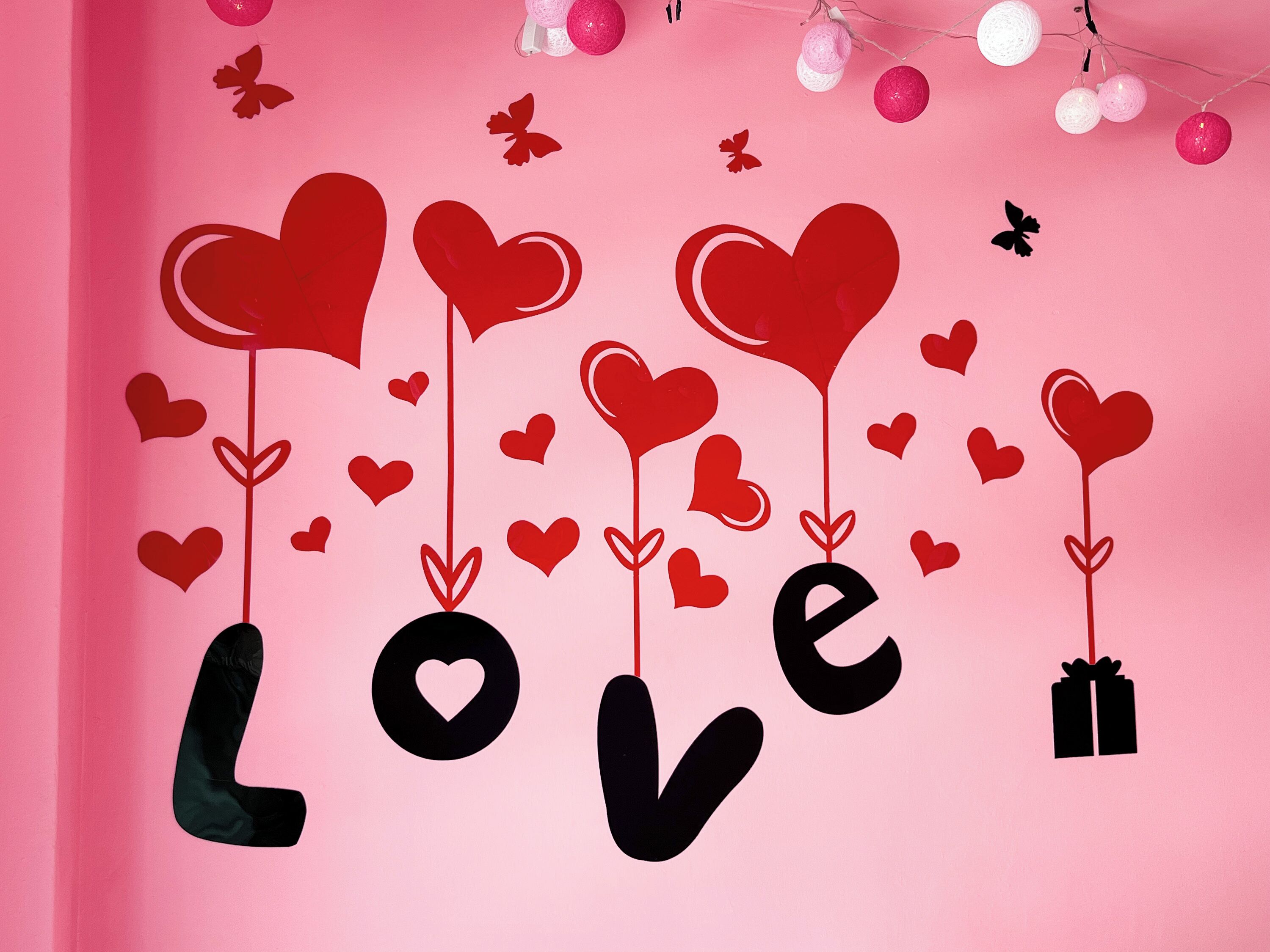 Paredes com a palavra 'LOVE' escrita em letras grandes, decoradas com corações e balões.