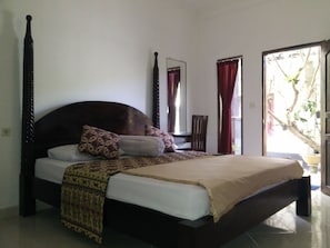 Uma cama com cabeceira, mesa de cabeceira, espelho e vista para o exterior.