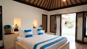 Quarto com cama grande, mesas de cabeceira e vista para o exterior.