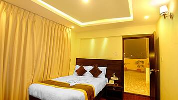 Quarto de hotel com uma cama, mesa de cabeceira e porta para uma varanda.