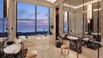 Um banheiro luxuoso com uma banheira grande, duas pias e um espelho amplo.