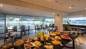Espaço de buffet com diversas opções de comida e vista para o exterior.