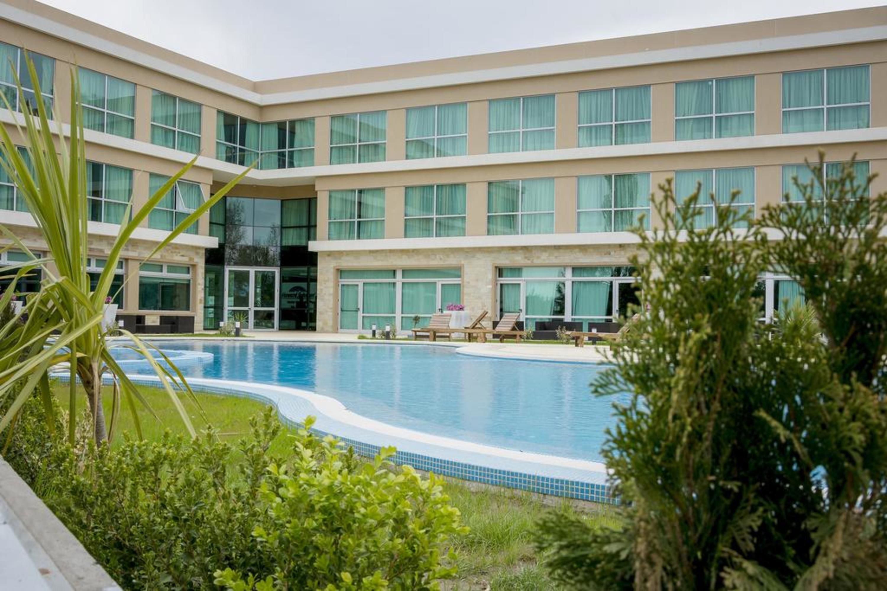 Um hotel com piscina, vários andares e grandes janelas.