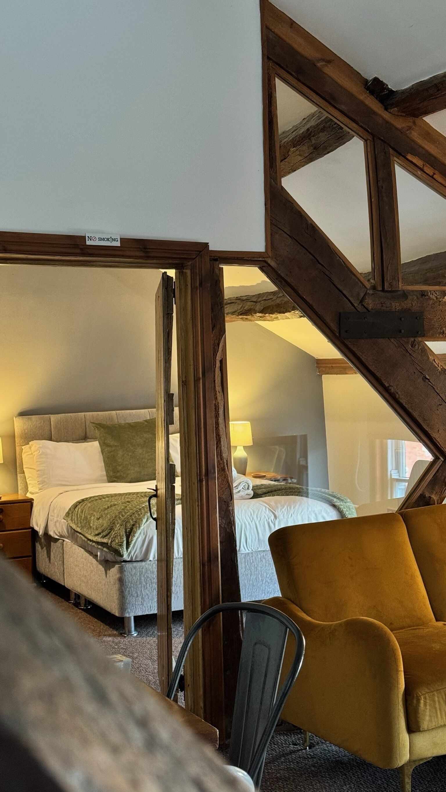 Quarto com cama, cadeira e escada.