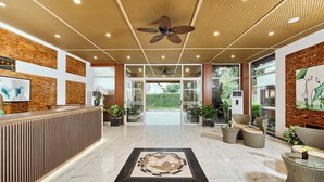 Uma área de recepção com design moderno, destacando um balcão de madeira, um ventilador de teto e uma grande porta de vidro que dá para o exterior.
