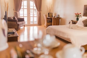 Quarto de hotel com uma cama, um sofá, uma escrivaninha e vista através de uma porta de vidro.