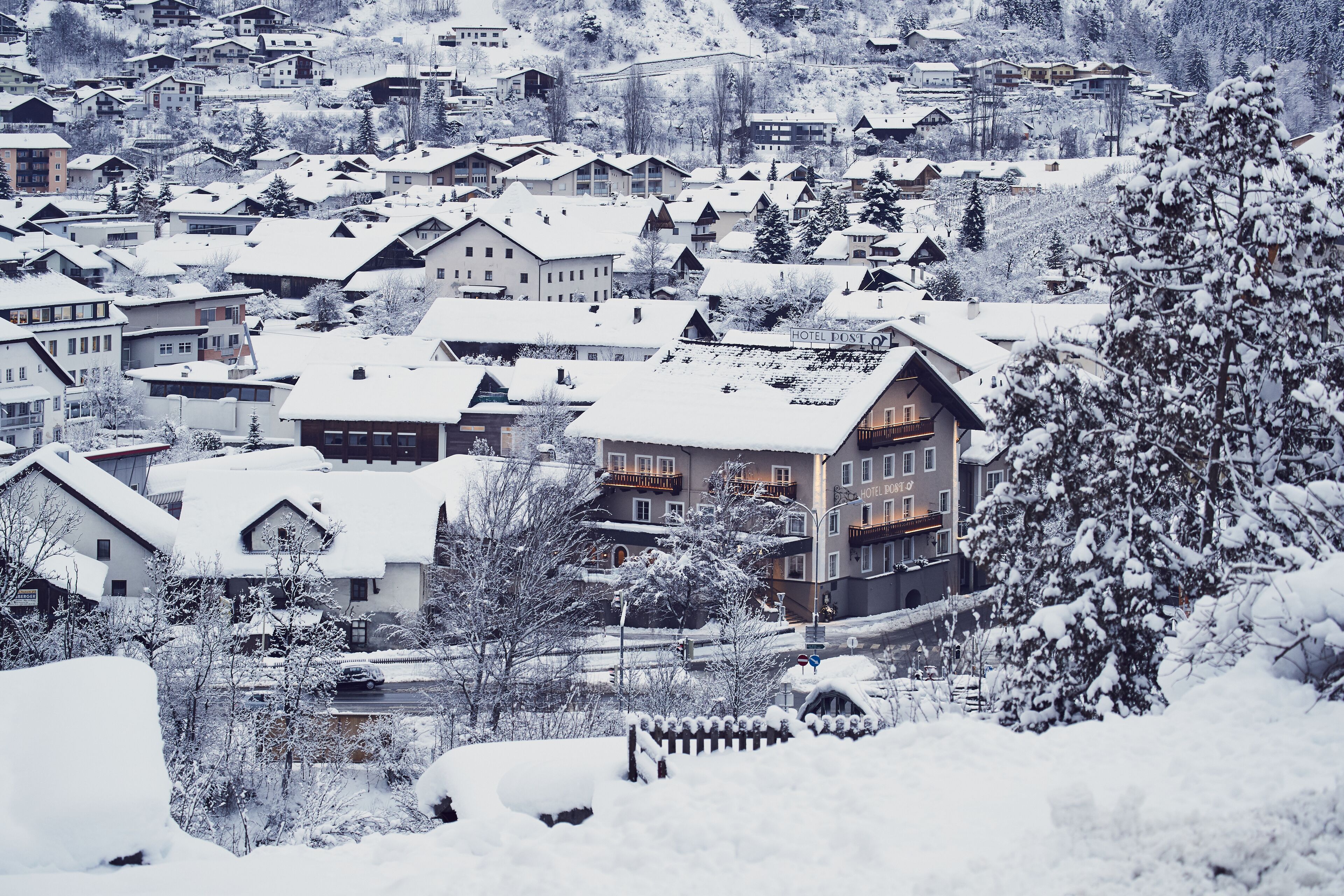 Uma área residencial coberta de neve, com várias casas e um hotel chamado "HOTEL DONT".