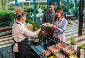 Restaurante com interior moderno, área de refeições em vidro e diversos ingredientes alimentares no balcão.